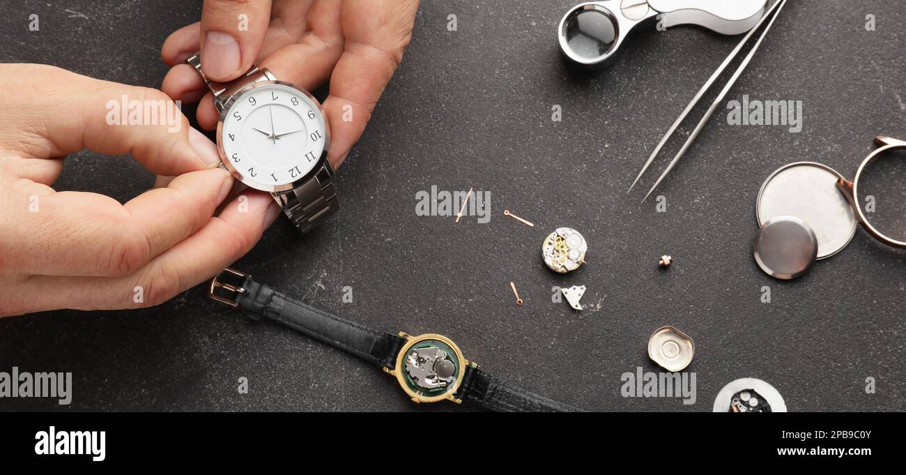 Clock maker's hands with broken watches and tools on dark background ...