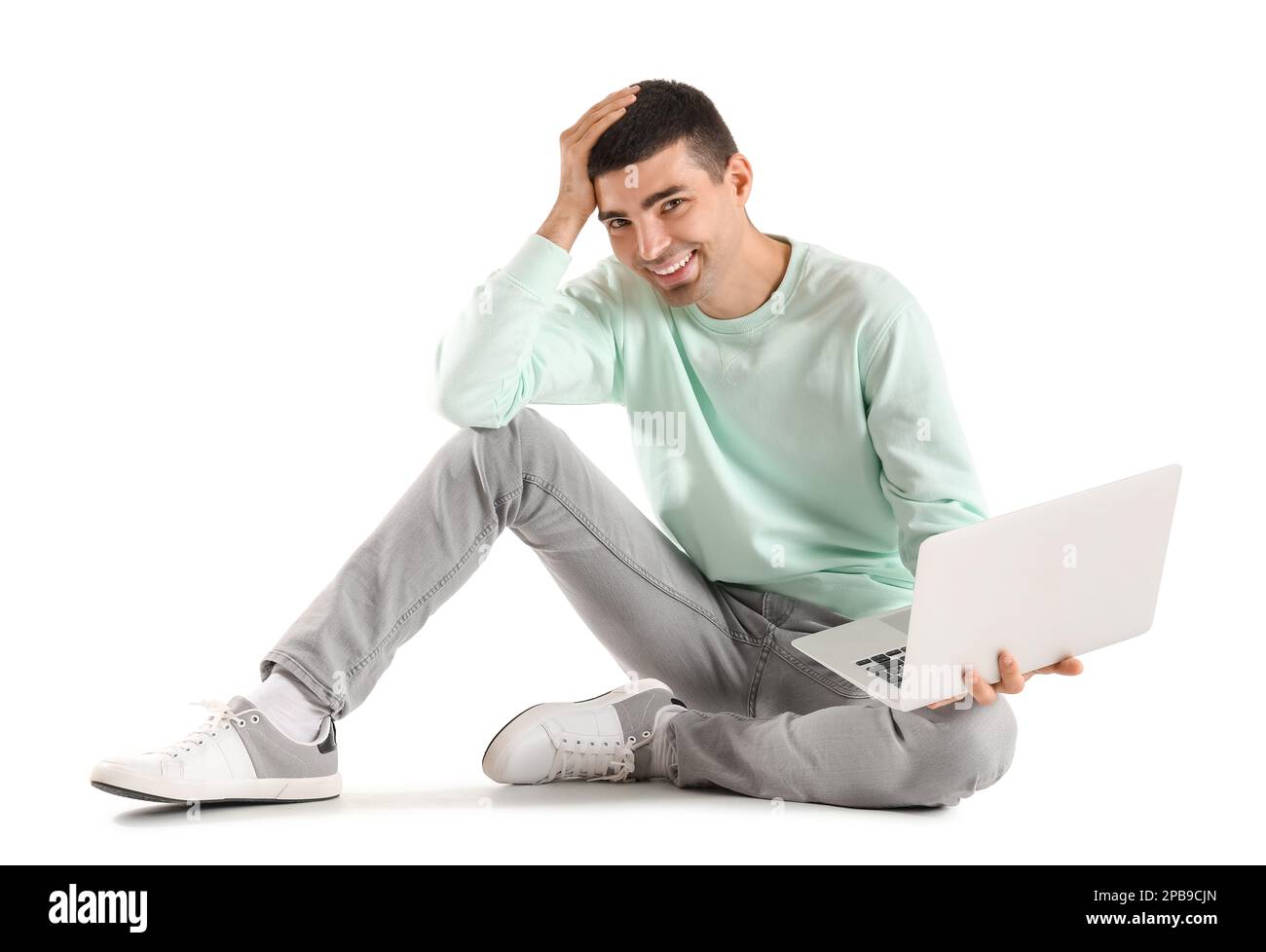 Handsome guy with laptop sitting on white background Stock Photo - Alamy