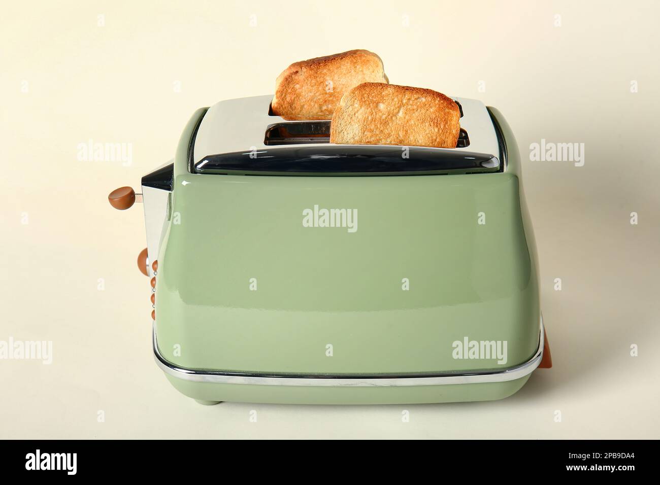 Modern toaster with crispy bread slices on beige background Stock Photo - Alamy