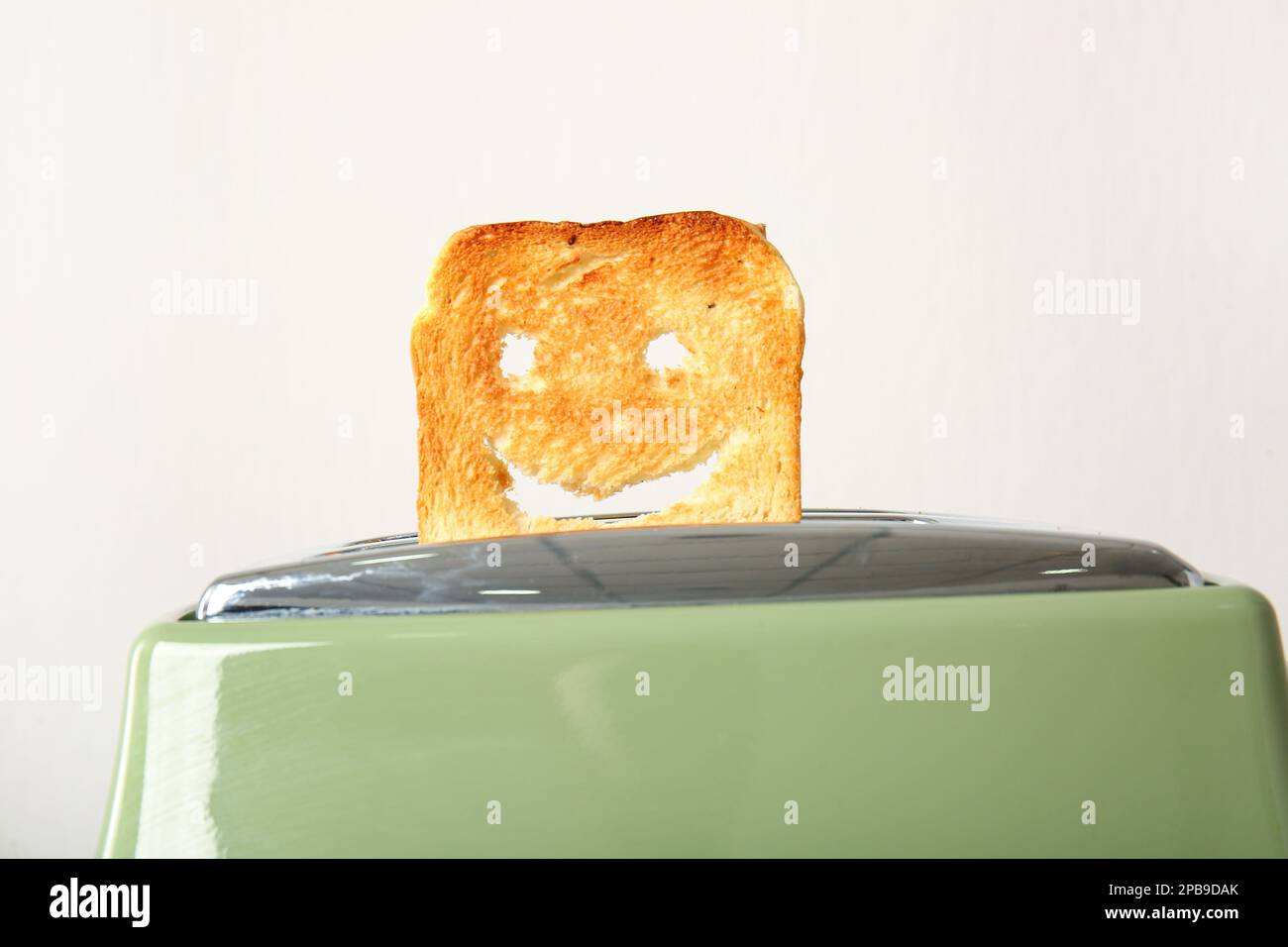 Funny slice of bread in modern toaster on white background Stock Photo ...