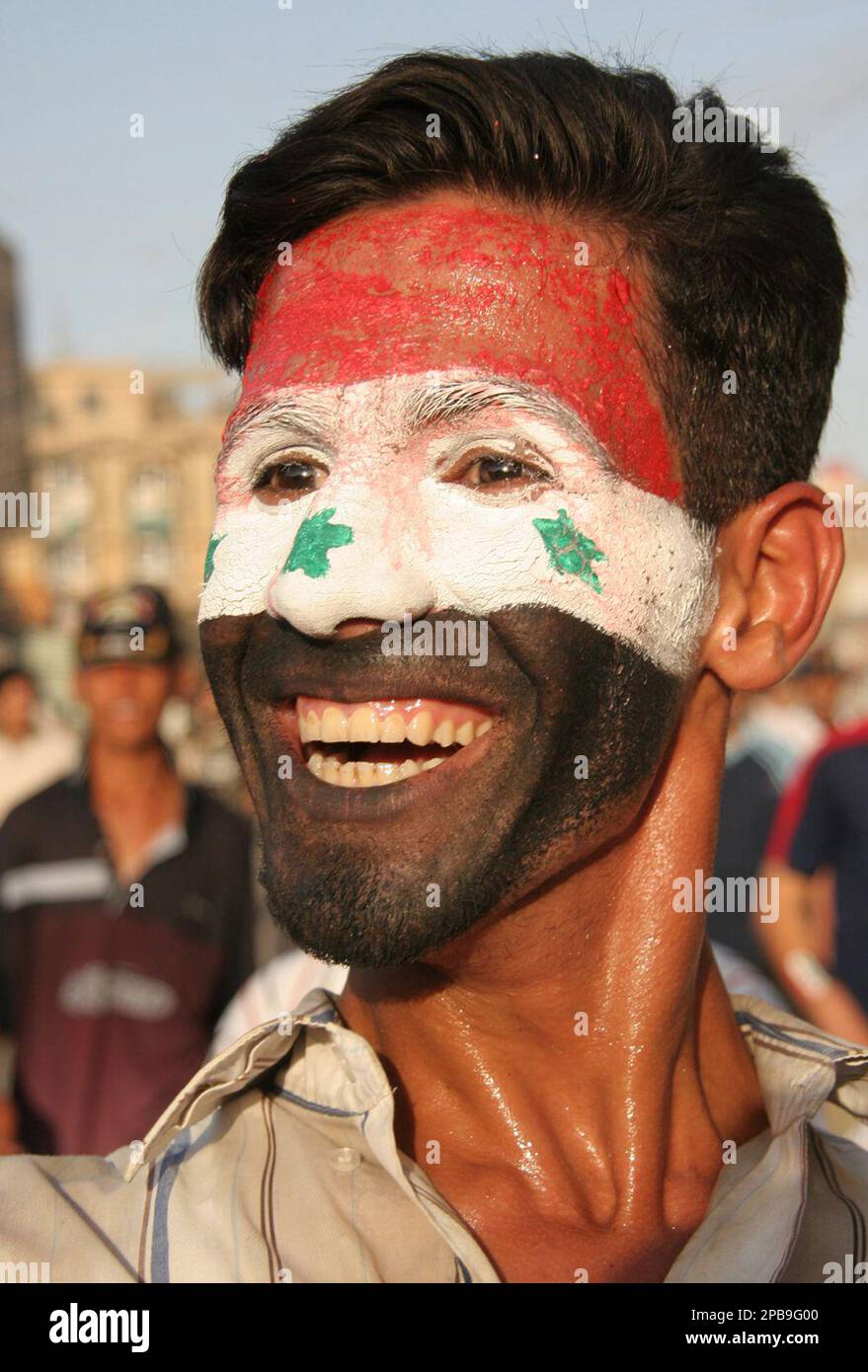 A man with painted Iraqi flag on his face smiles during celebrations ...