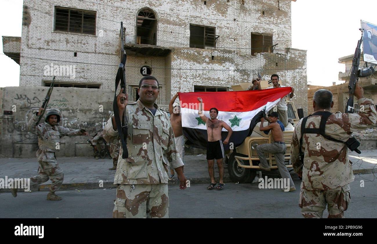 Iraqi soldiers shoot in the air as people, waving Iraqi flag, celebrate ...