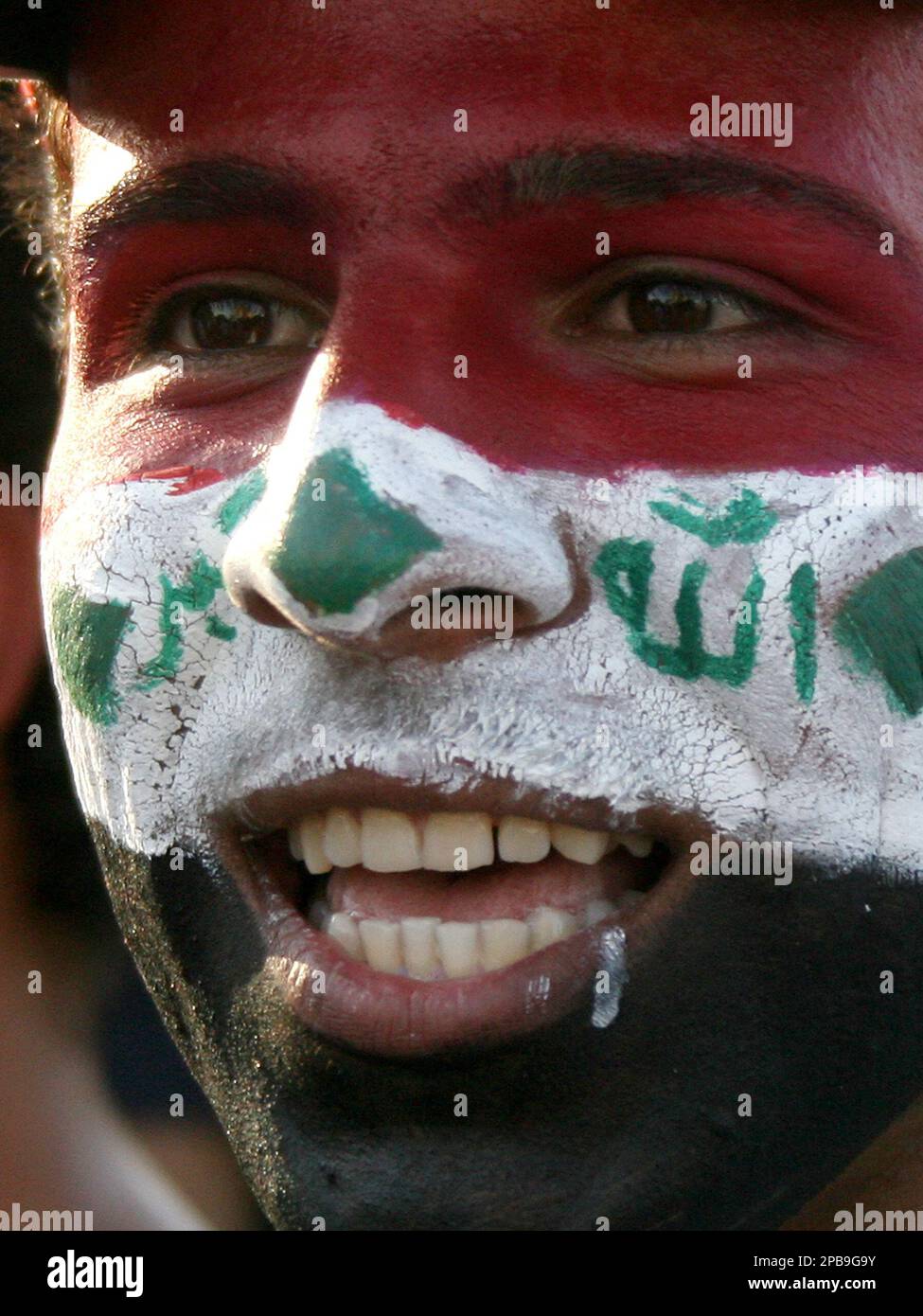 A young man with painted Iraqi flag on his face celebrates in streets ...
