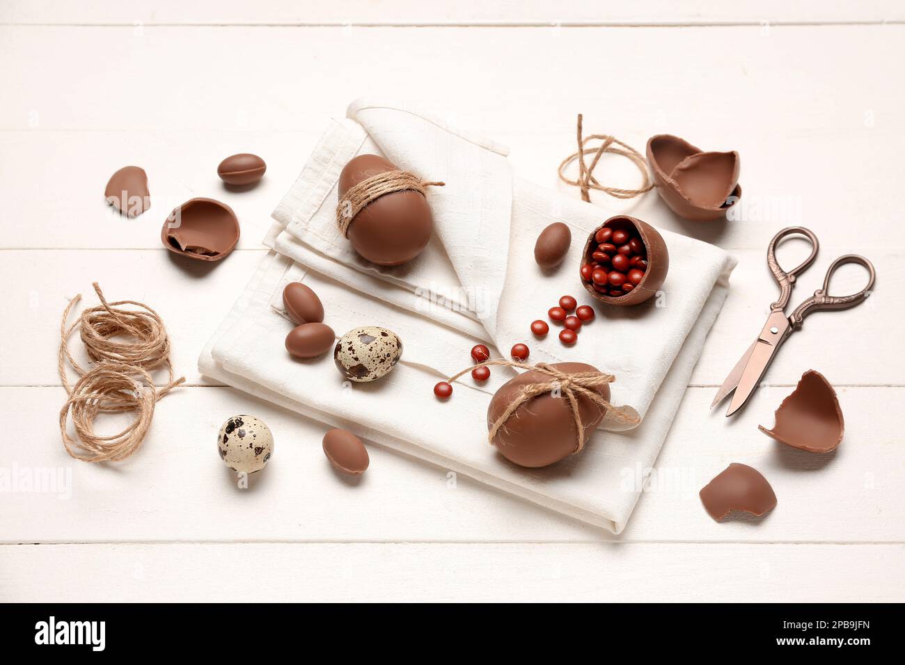 Composition with chocolate Easter eggs, candies, thread and scissors on ...