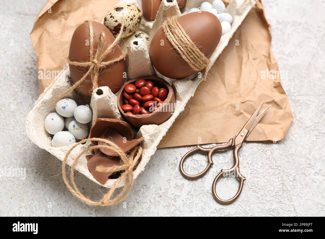 Composition with chocolate Easter eggs, candies, thread and scissors on ...