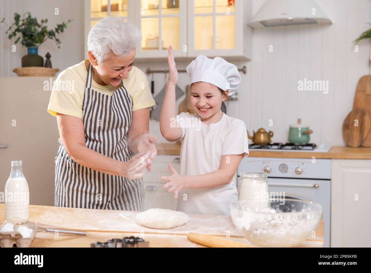 Happy family in kitchen. Grandmother and granddaughter child cook in ...
