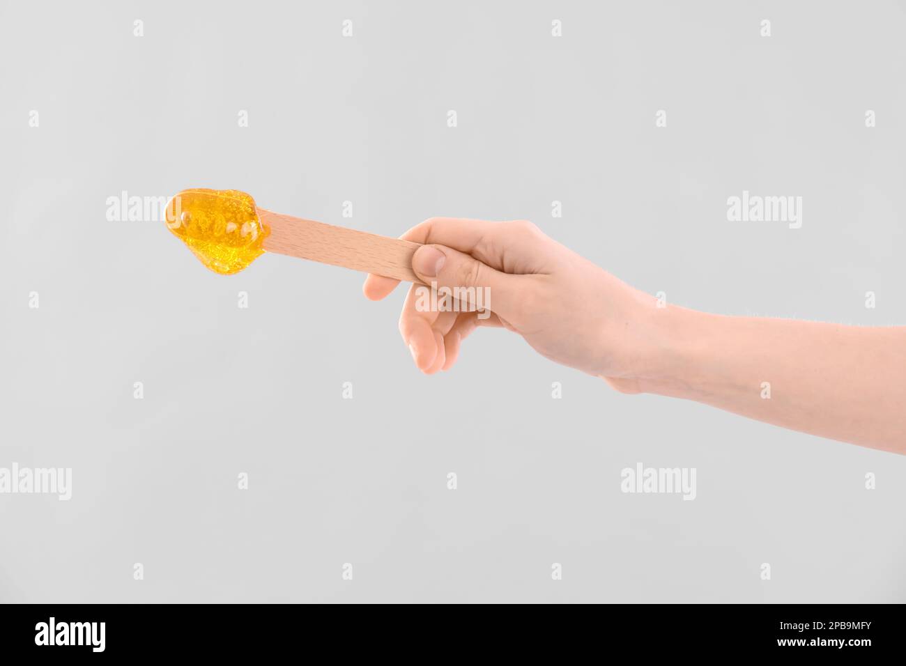 Hand holding spatula with sugaring paste on light background Stock ...