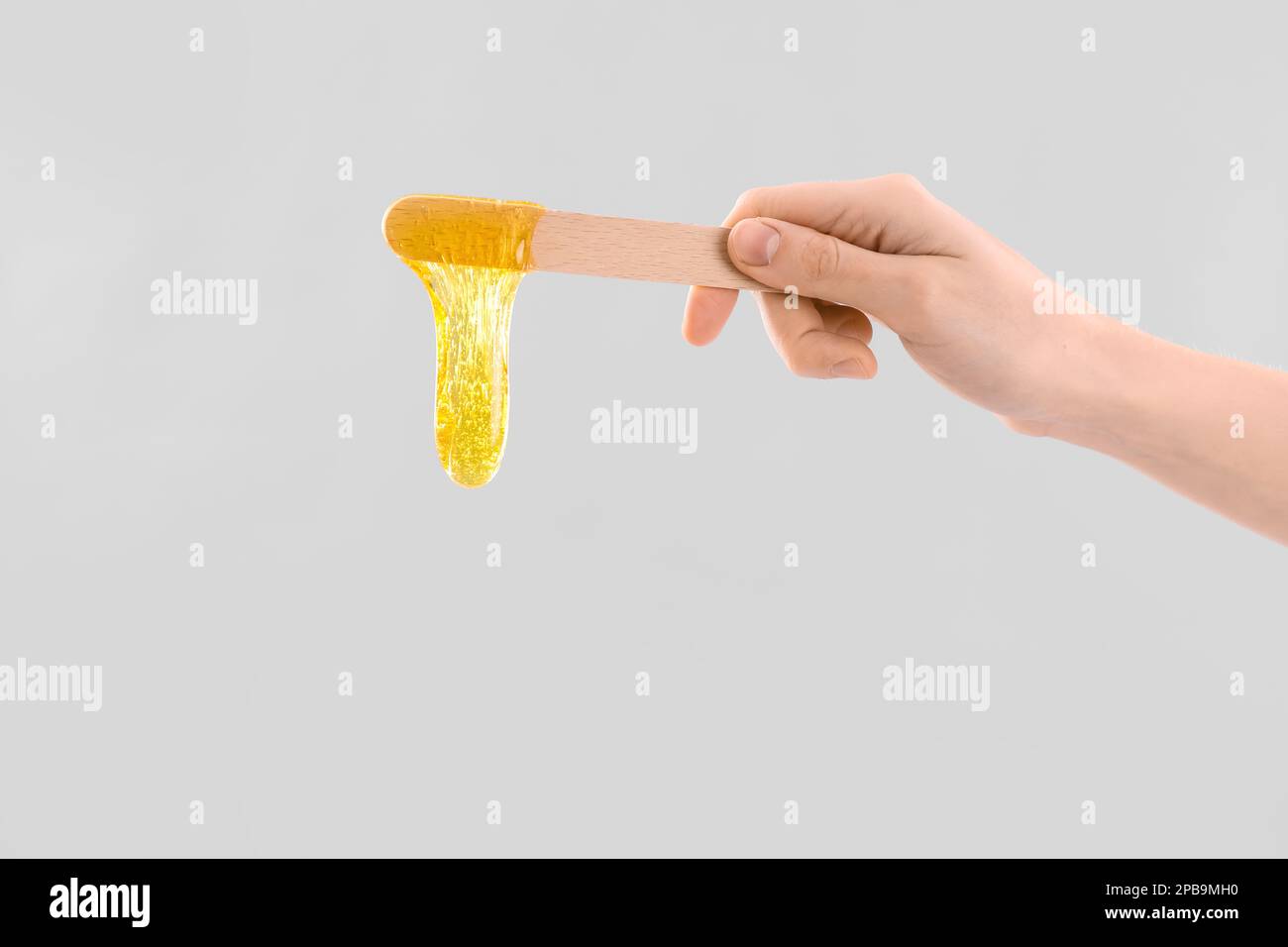Hand holding spatula with sugaring paste on light background Stock ...