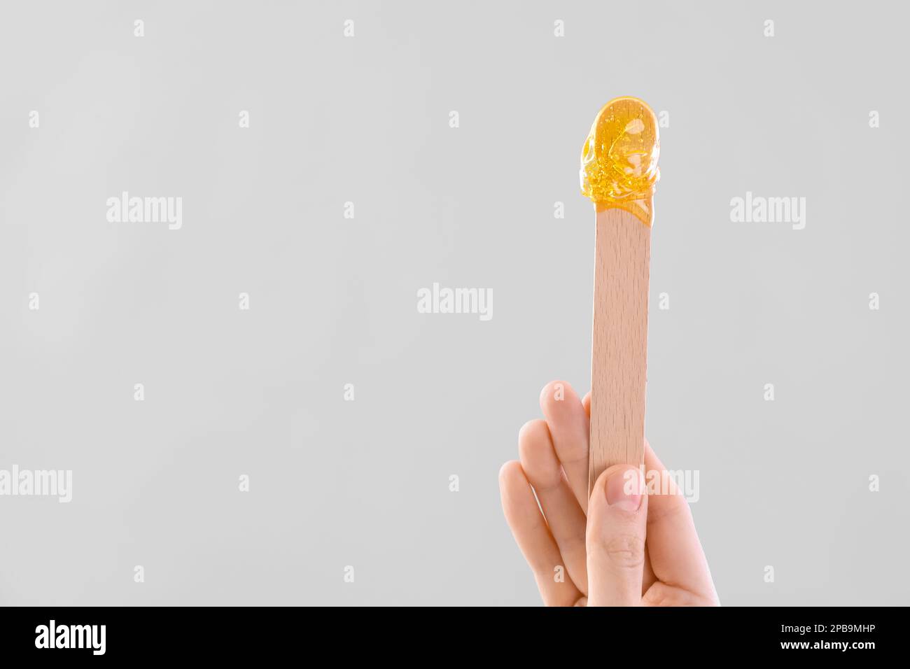 Hand holding spatula with sugaring paste on light background Stock ...