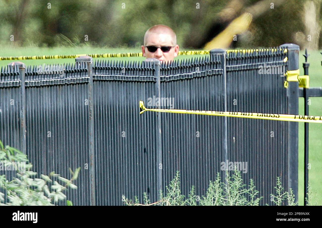 A Phoenix police officer stands inside the police tape at a two ...