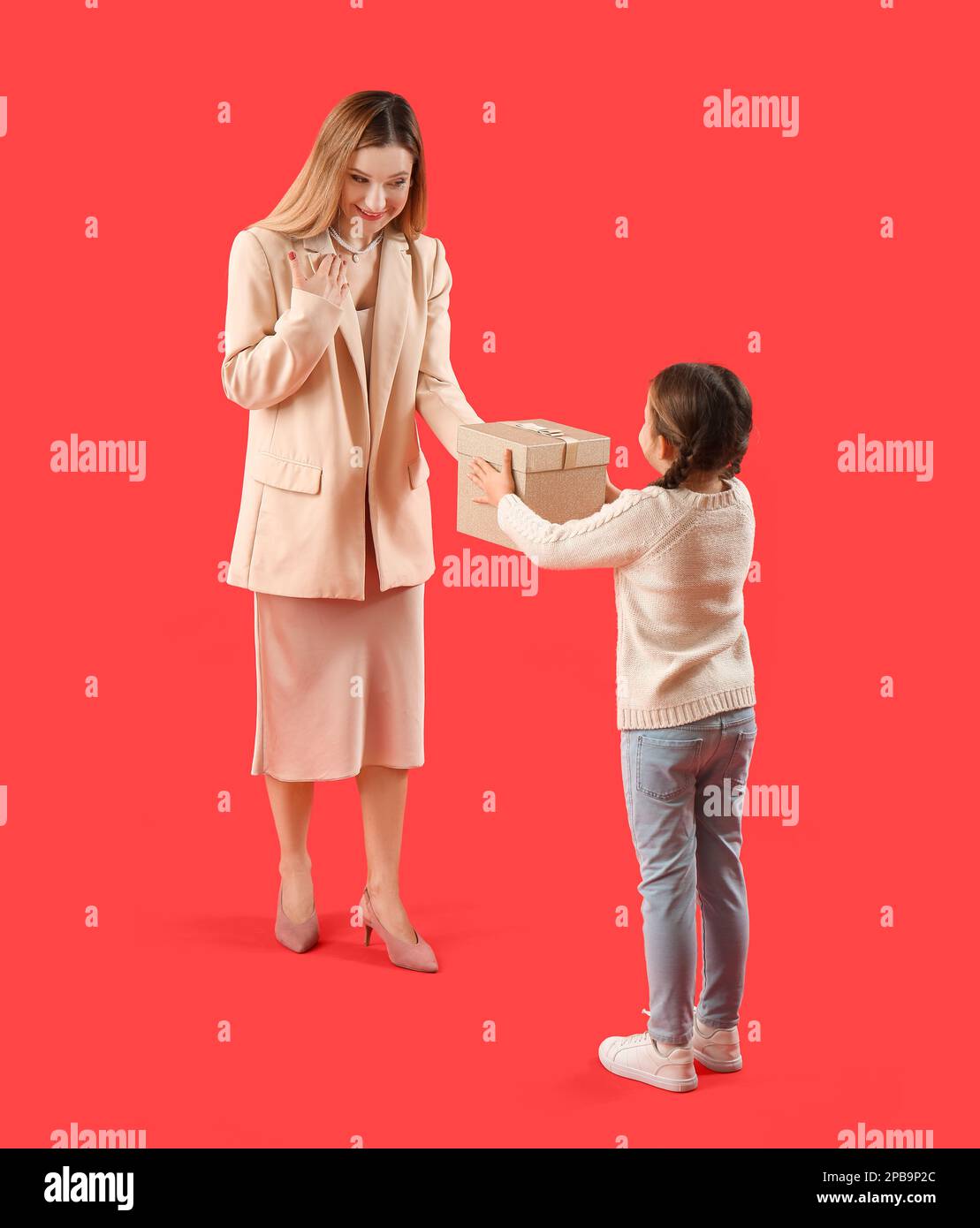 Cute little girl greeting her mother with gift on red background Stock ...