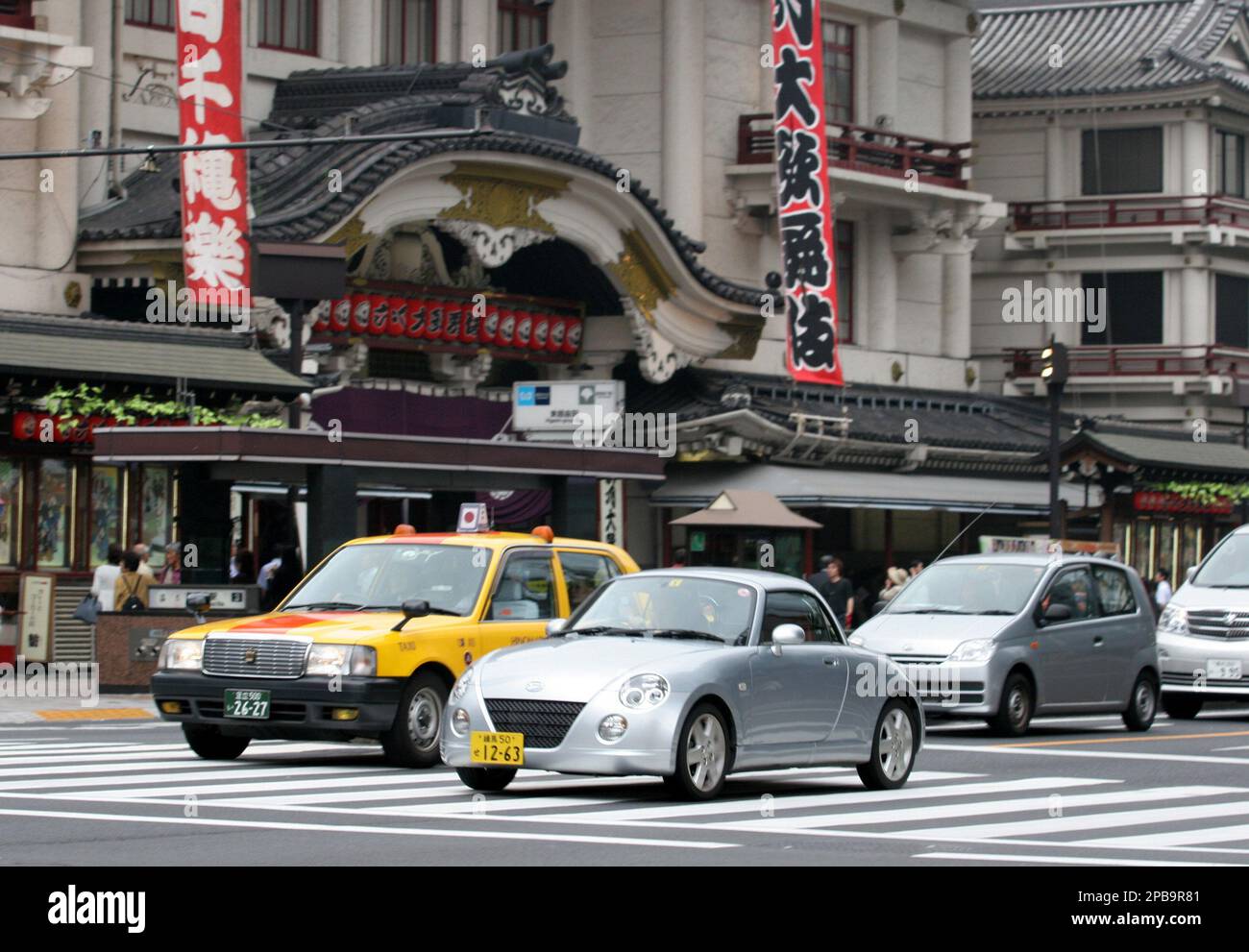 Japanese minicars drive by the Kabuki Theater in downtown Tokyo Monday ...