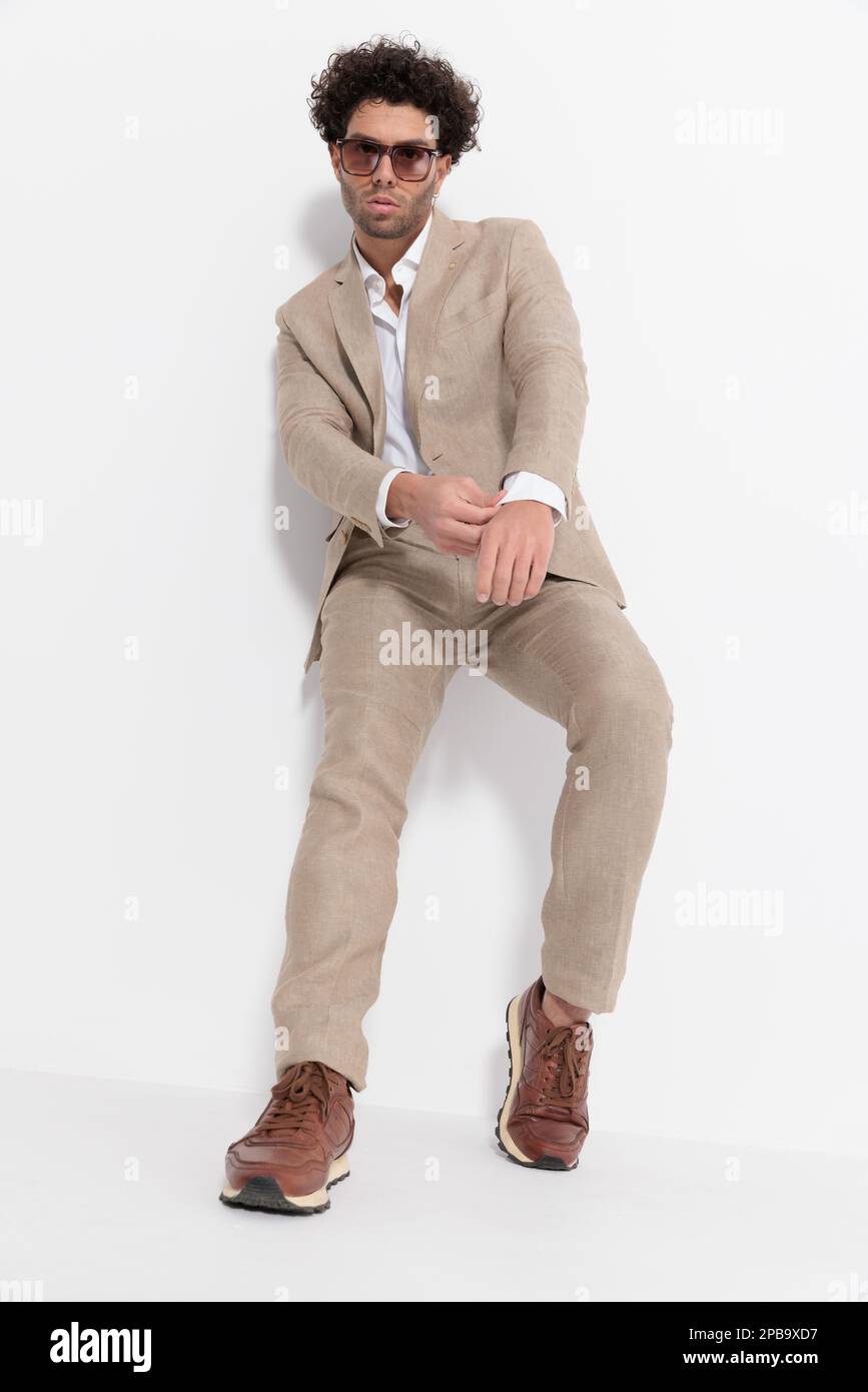 full body picture of curly hair man with open collar shirt adjusting ...