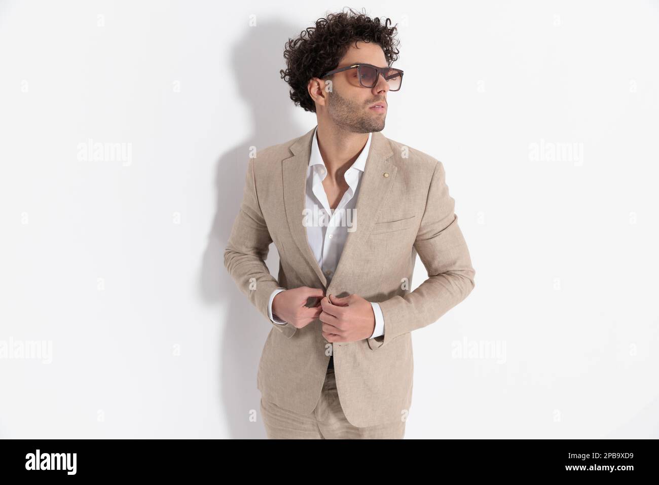 smart casual man with open collar shirt looking to side and buttoning ...