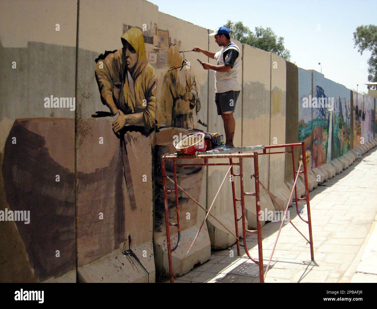 An Iraqi artist commissioned by the government paints a mural on a ...