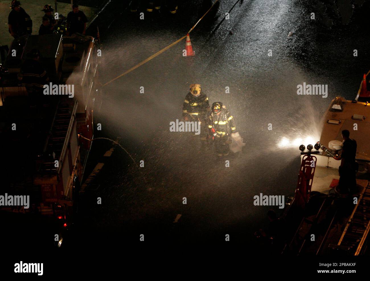 Firemen walk through a stream of water to clean off after a steam ...