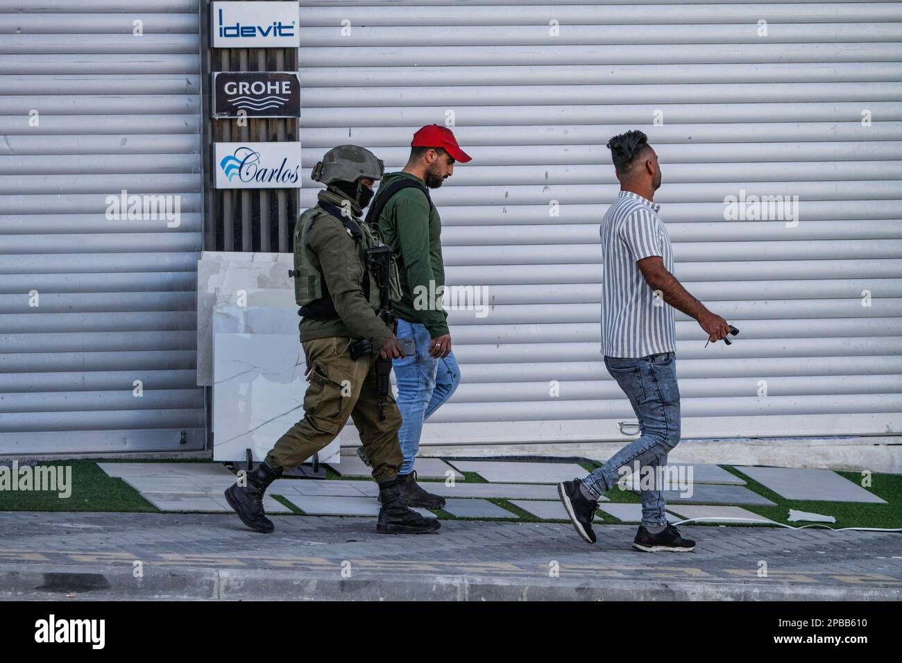 Nablus, Palestine. 12th Mar, 2023. An Israeli soldier arrests two ...