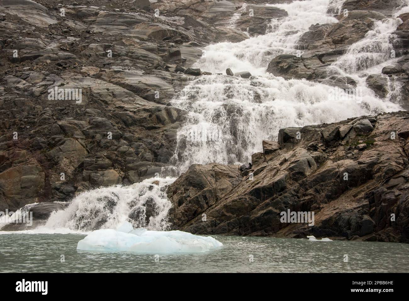 Water cascading down a rocky cliff with a blue growler, near Jorge ...