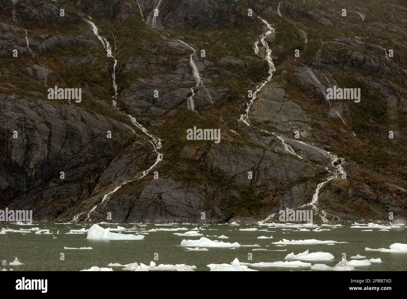 Waterfalls snaking down a rocky cliff into the Baker Channel and the ...