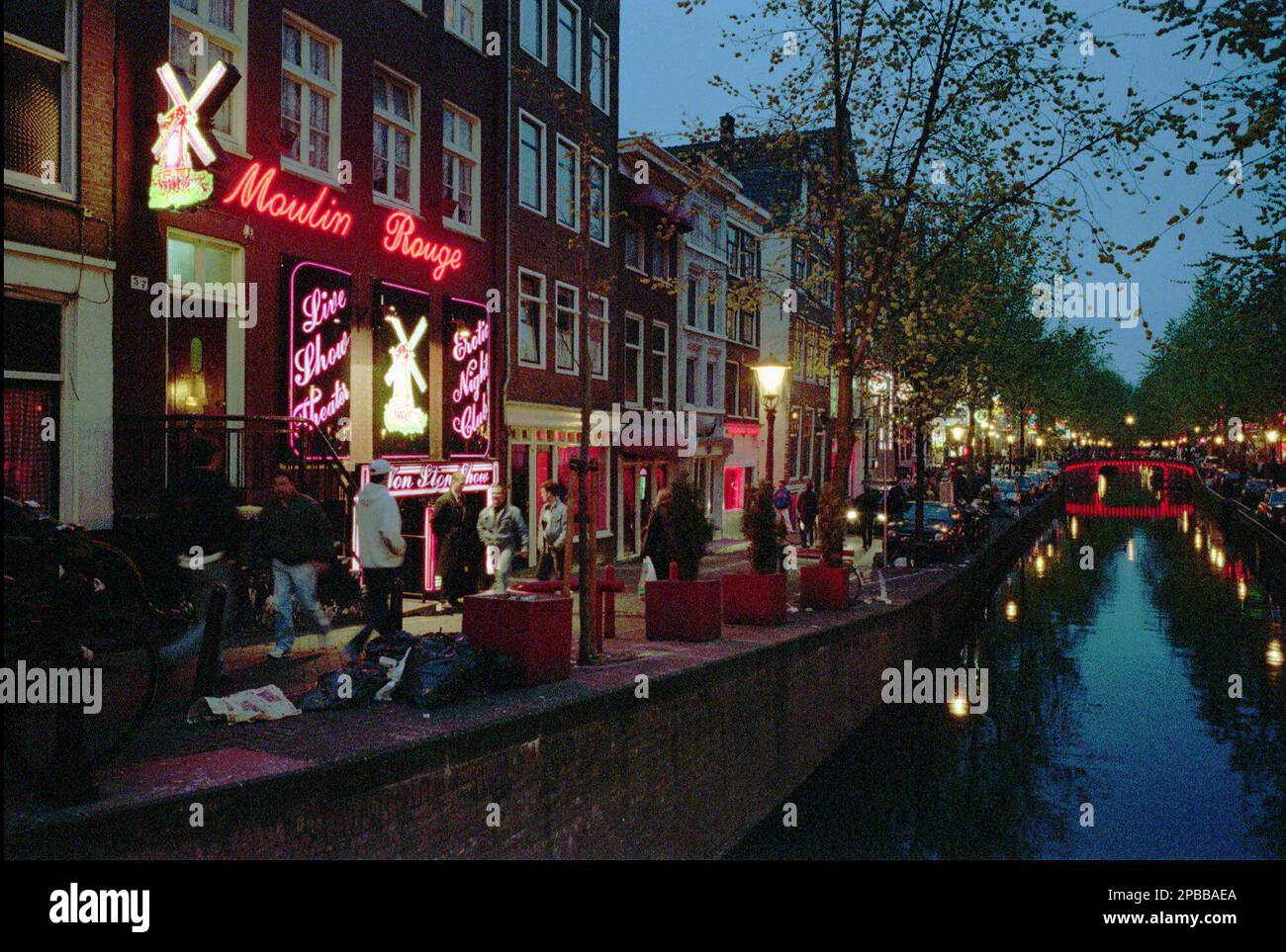 FILE - Prostitutes stand behind red-lit windows, waiting for customers ...