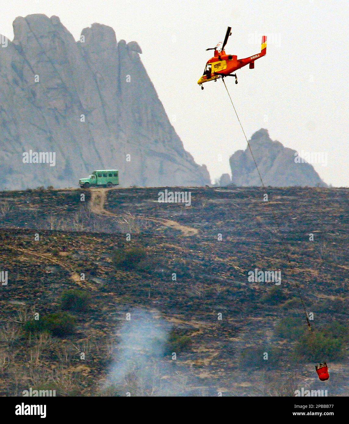A fire fighting vehicle sits on top of a burned out ridgeline as a ...