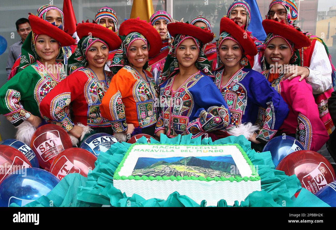 People dressed in traditional Andean costumes pose with a cake ...