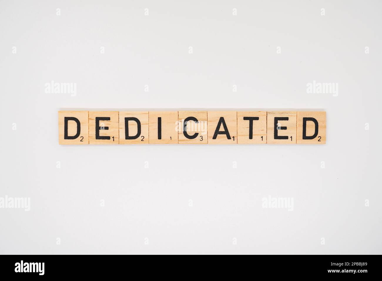 Wooden title spelling the word dedicated isolated on a white background ...