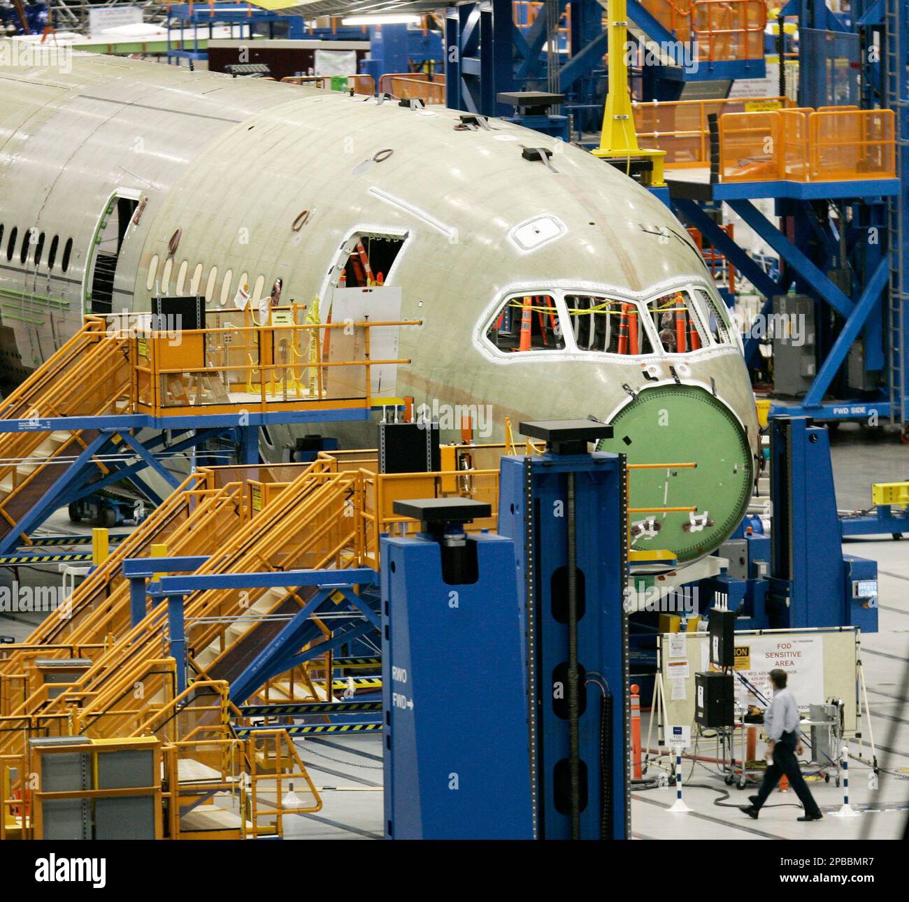 A worker walks by a Boeing 787 being built, Saturday, July 7, 2007, at ...