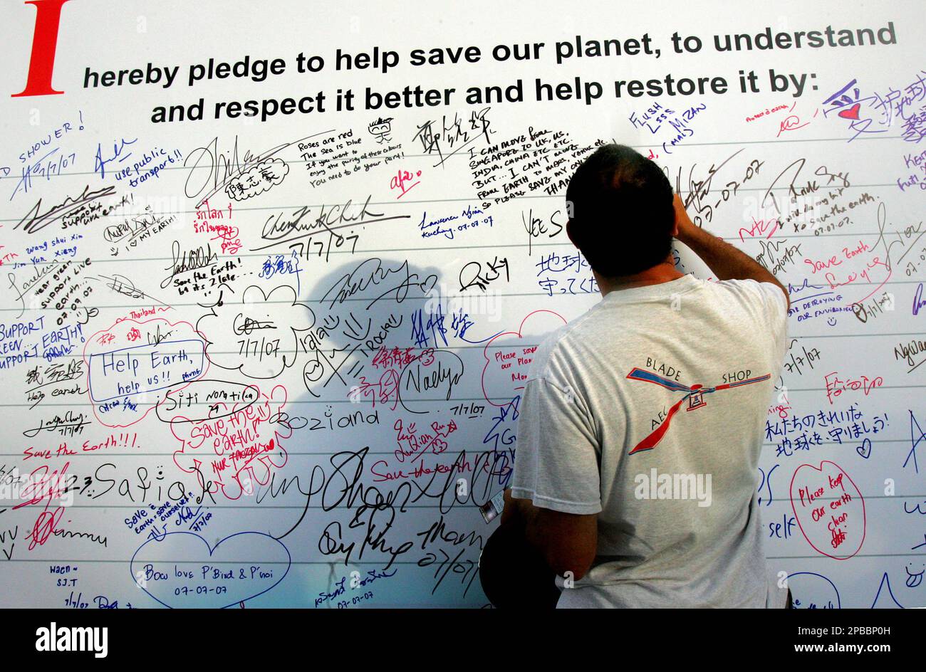 A man signs a pledge board to do his part to save and restore the earth ...