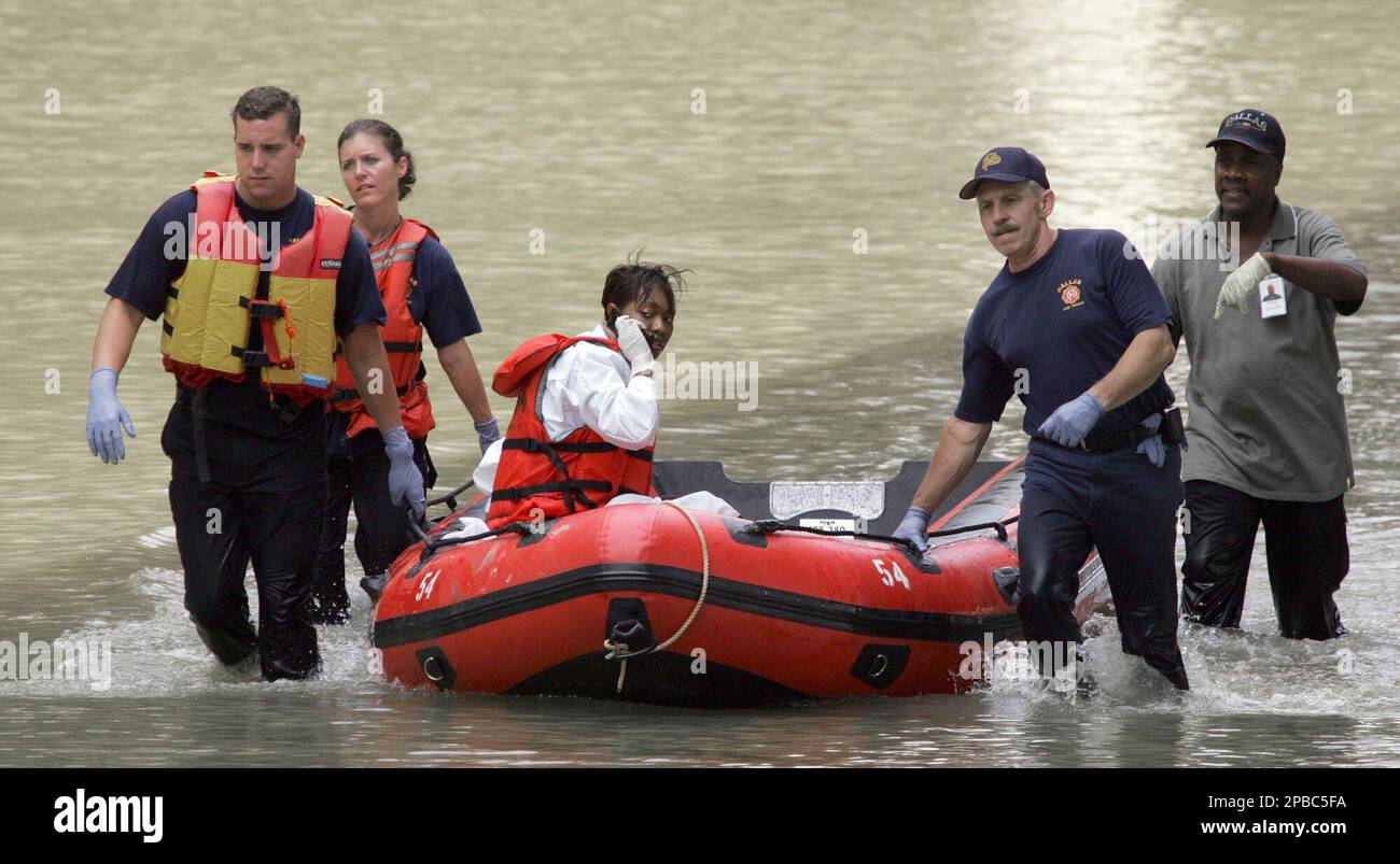 Dallas firefighters push an inflatable boat bearing the recovered body ...