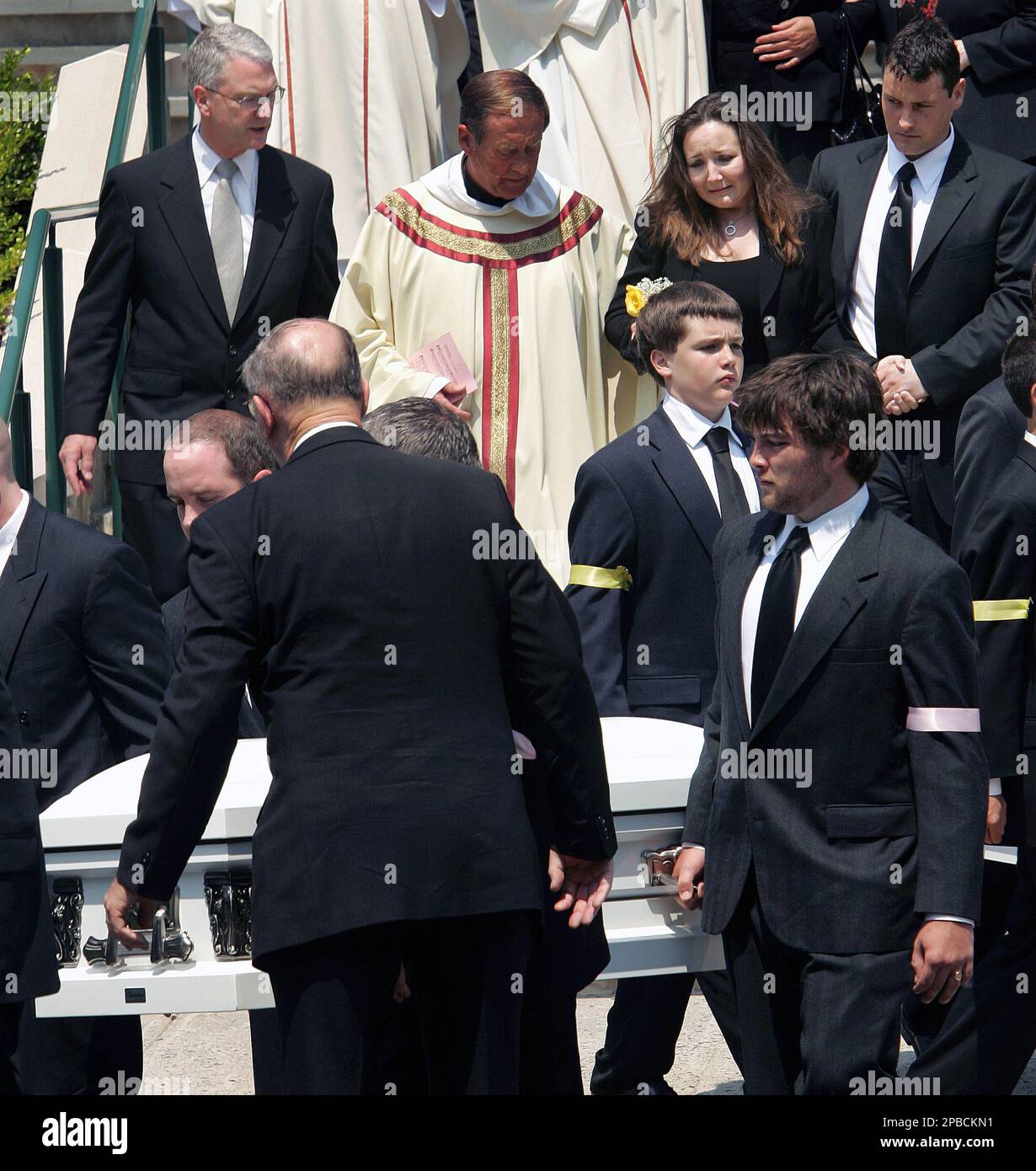 Teresa Reilly is helped by a priest as she follows the casket of one of ...