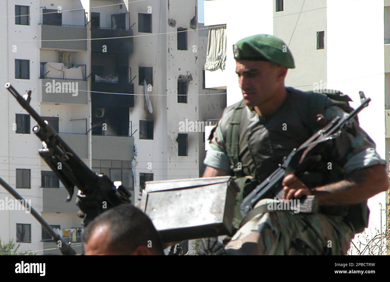 A Lebanese army soldier sits on top of an armored vehicle in front of ...