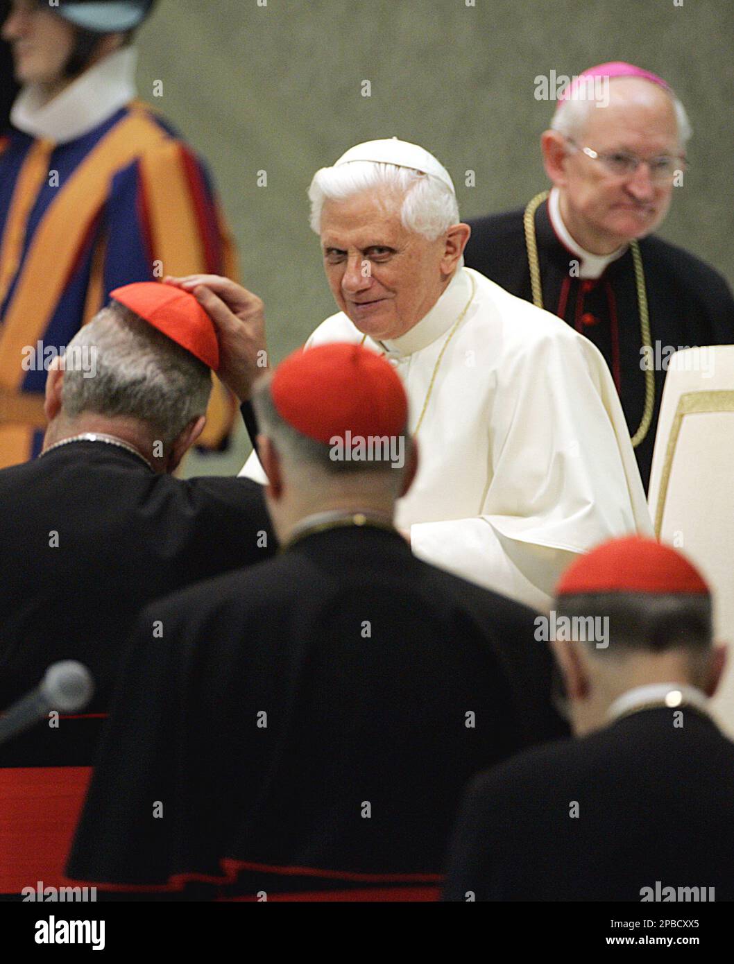 A Cardinal takes off his red skull cap as he approaches Pope Benedict ...