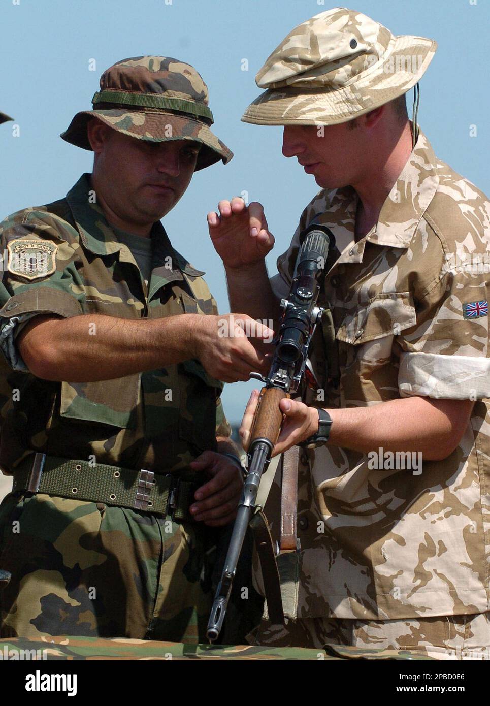 Holding an AK 47 rifle, a British soldier, right, talks with Macedonian ...