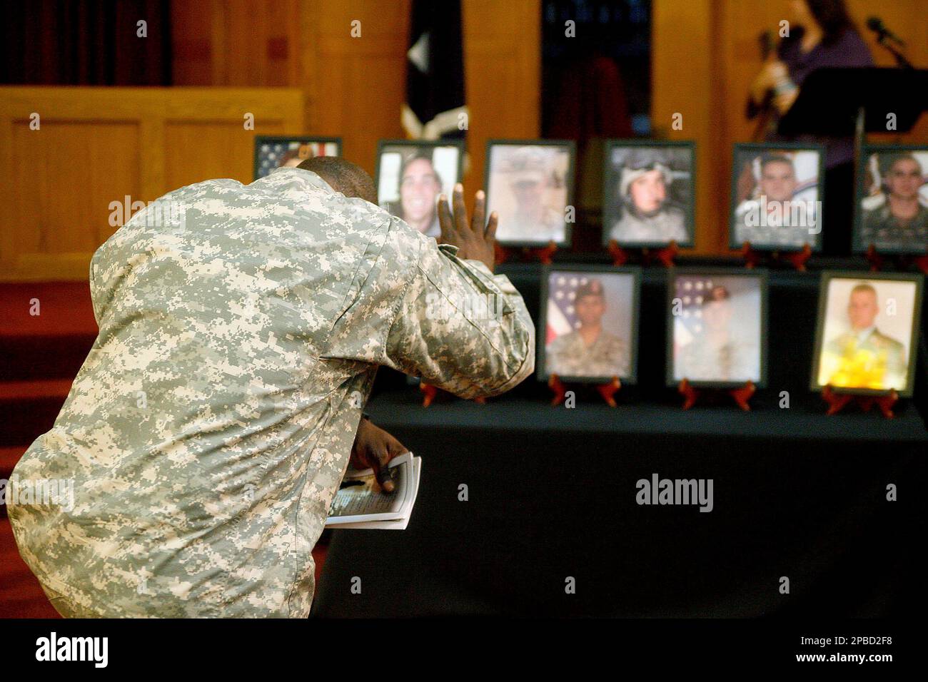 Lt. Col. Nathaniel Rivers prays in front of a display with the photos ...