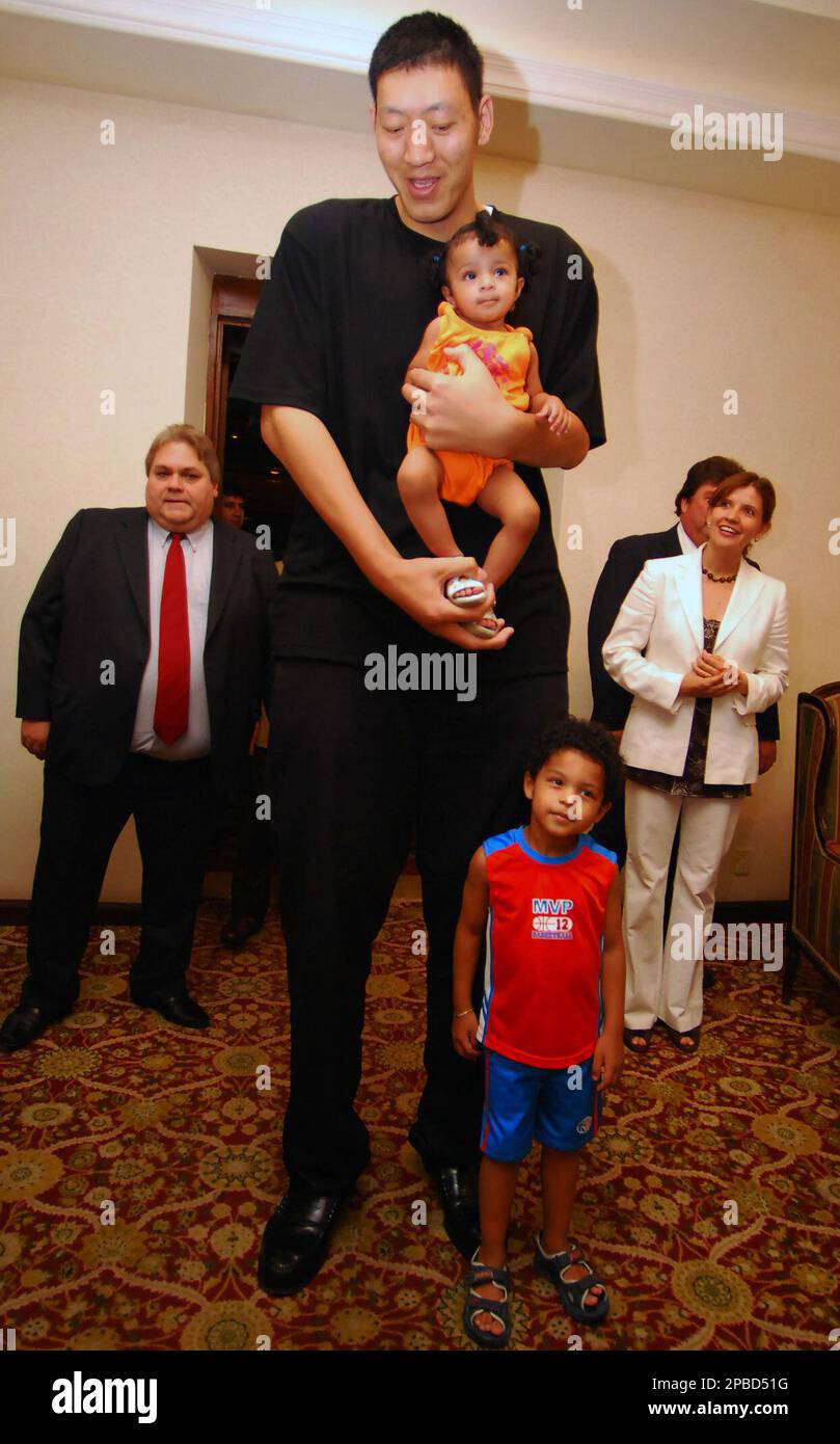 Seven-foot-nine-inch Chinese basketball player Sun Ming Ming poses with children at a news ...