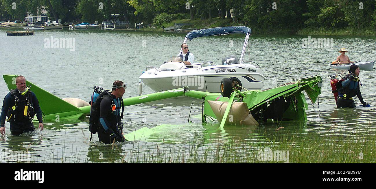 Divers walk ashore near the wreckage of an ultra-light aircraft that ...