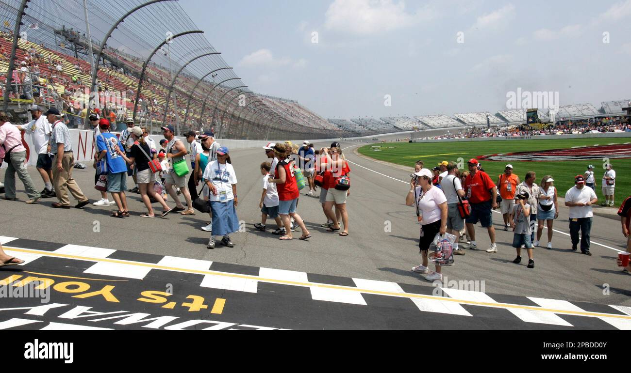 NASCAR fans walk up the finish line incline after touring the pit area ...