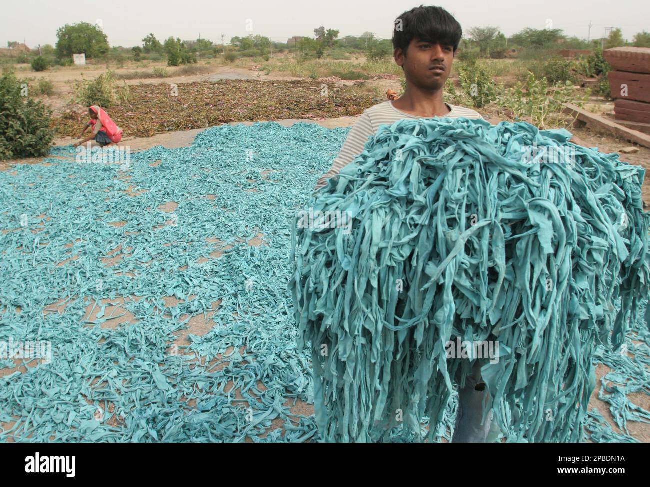 A man carries shredded clothes, a byproduct of the textile industry ...