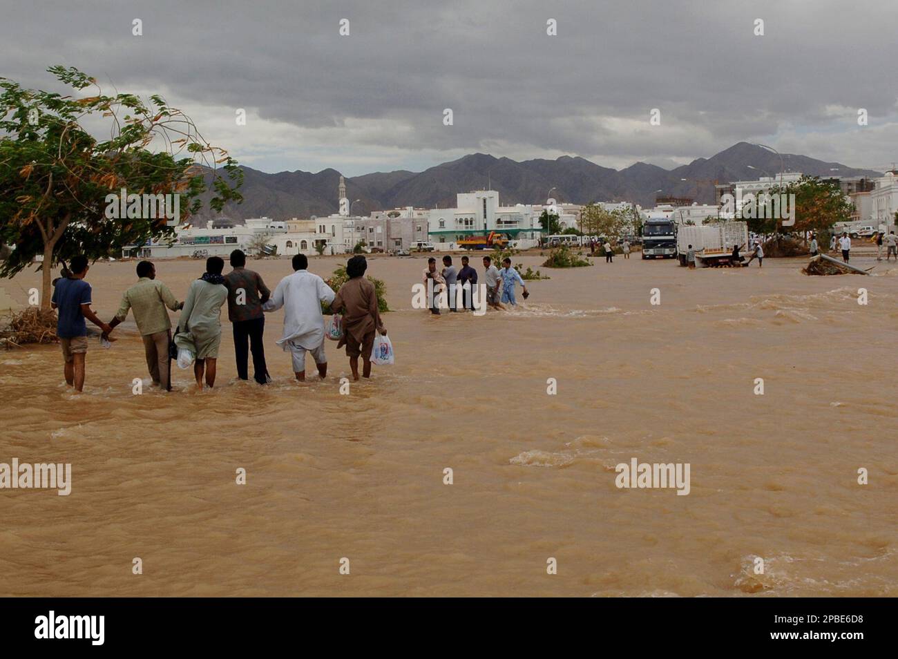 People wade through flood water in Muscat, the Sultanate of Oman ...