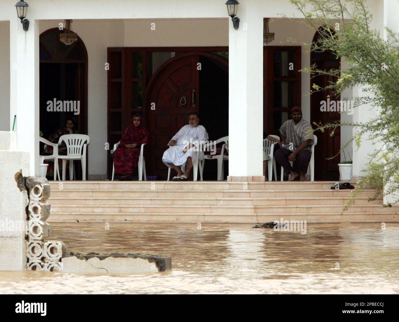 A family look at the flood passing by their home in Muscat, Oman ...