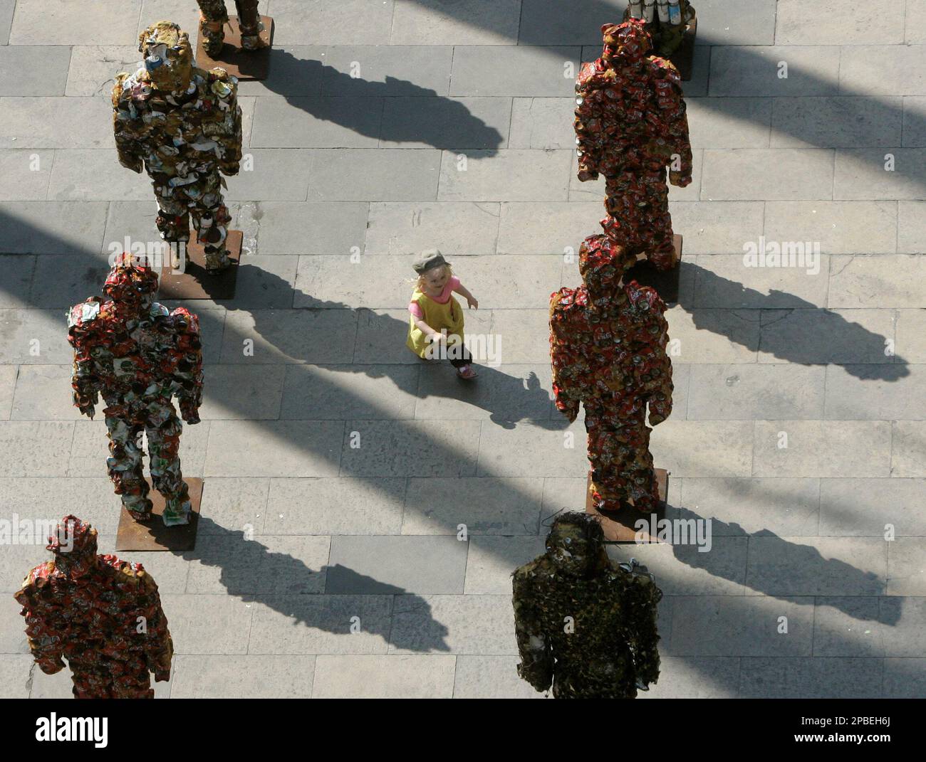 A girl walks between rows of life-sized mannequins made of waste ...