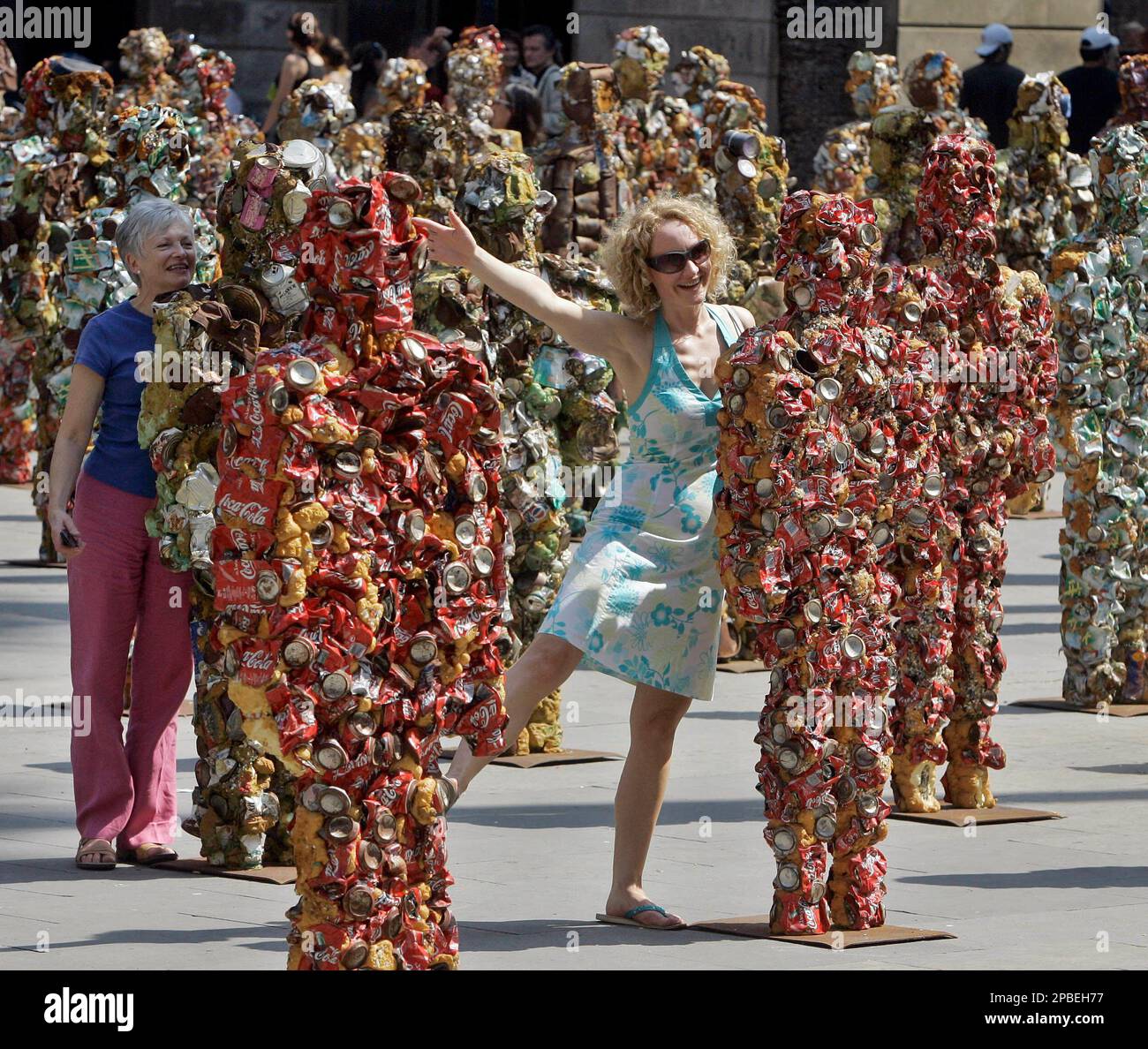 Two women pose for photos between rows of life-sized mannequins made of ...