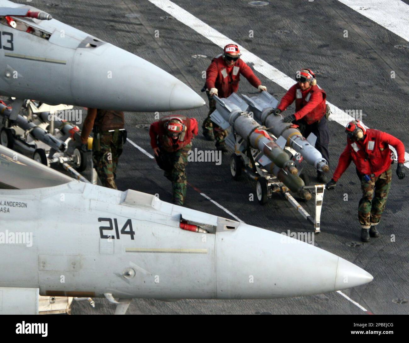 U.S. Navy personnel push missiles aboard the USS Nimitz on Monday, June ...