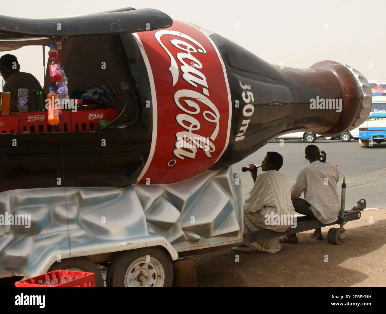 A Sudanese man drinks Coca-Cola under a bottle-shaped drinks stall in ...