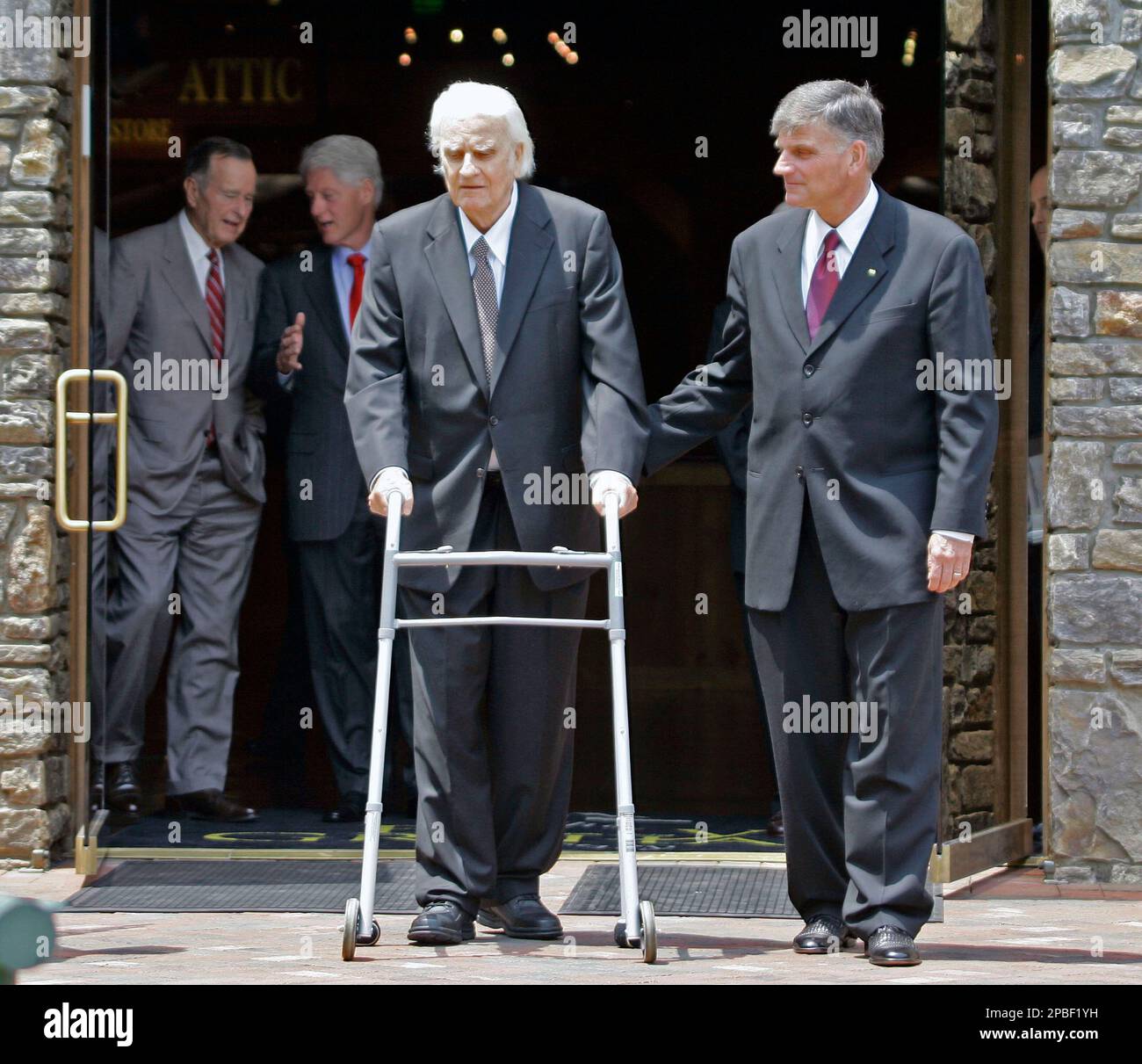Franklin Graham, right, helps his father Billy Graham, center, followed ...