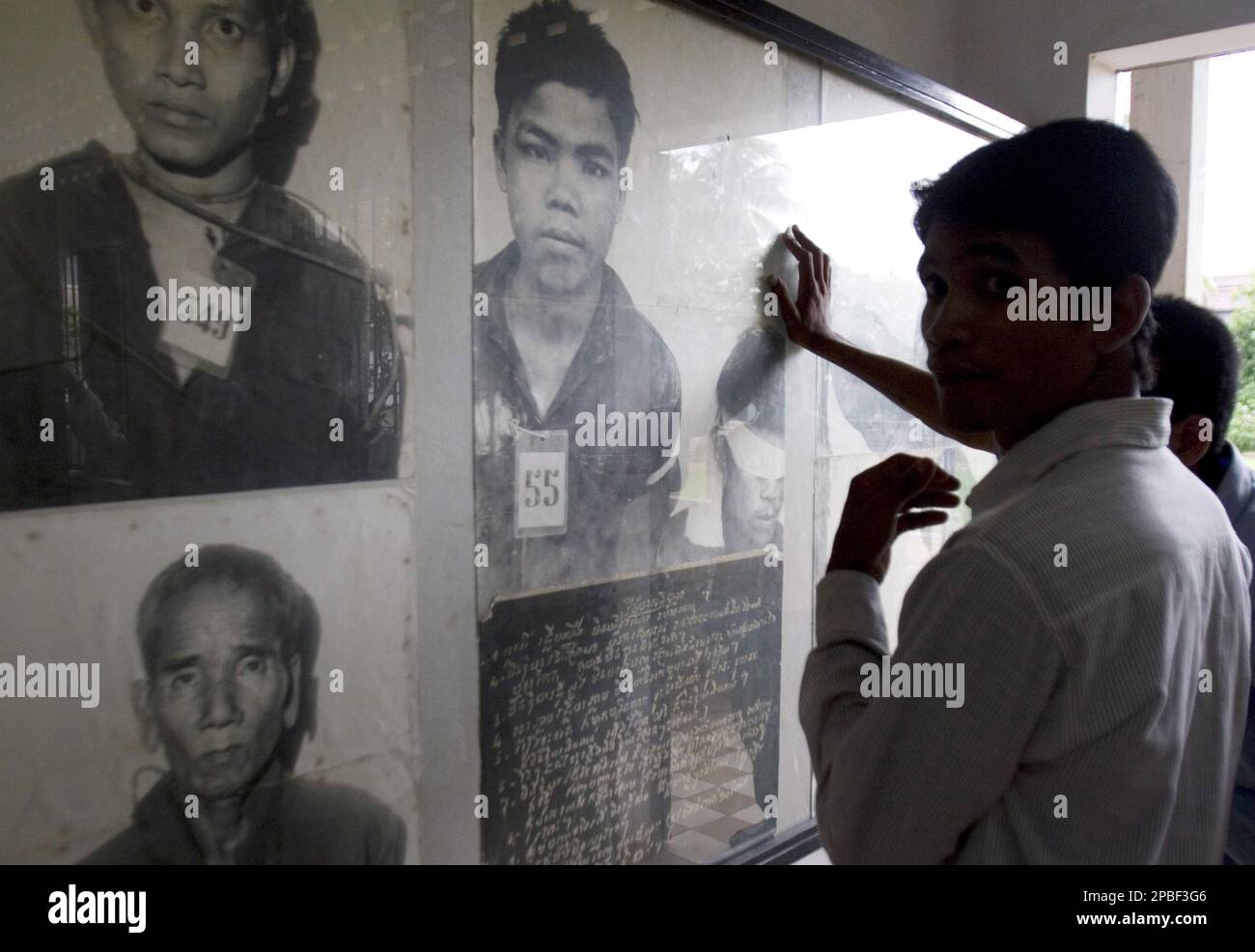 Cambodian men view portraits of Khmer Rouge's victims at Tuol Sleng ...