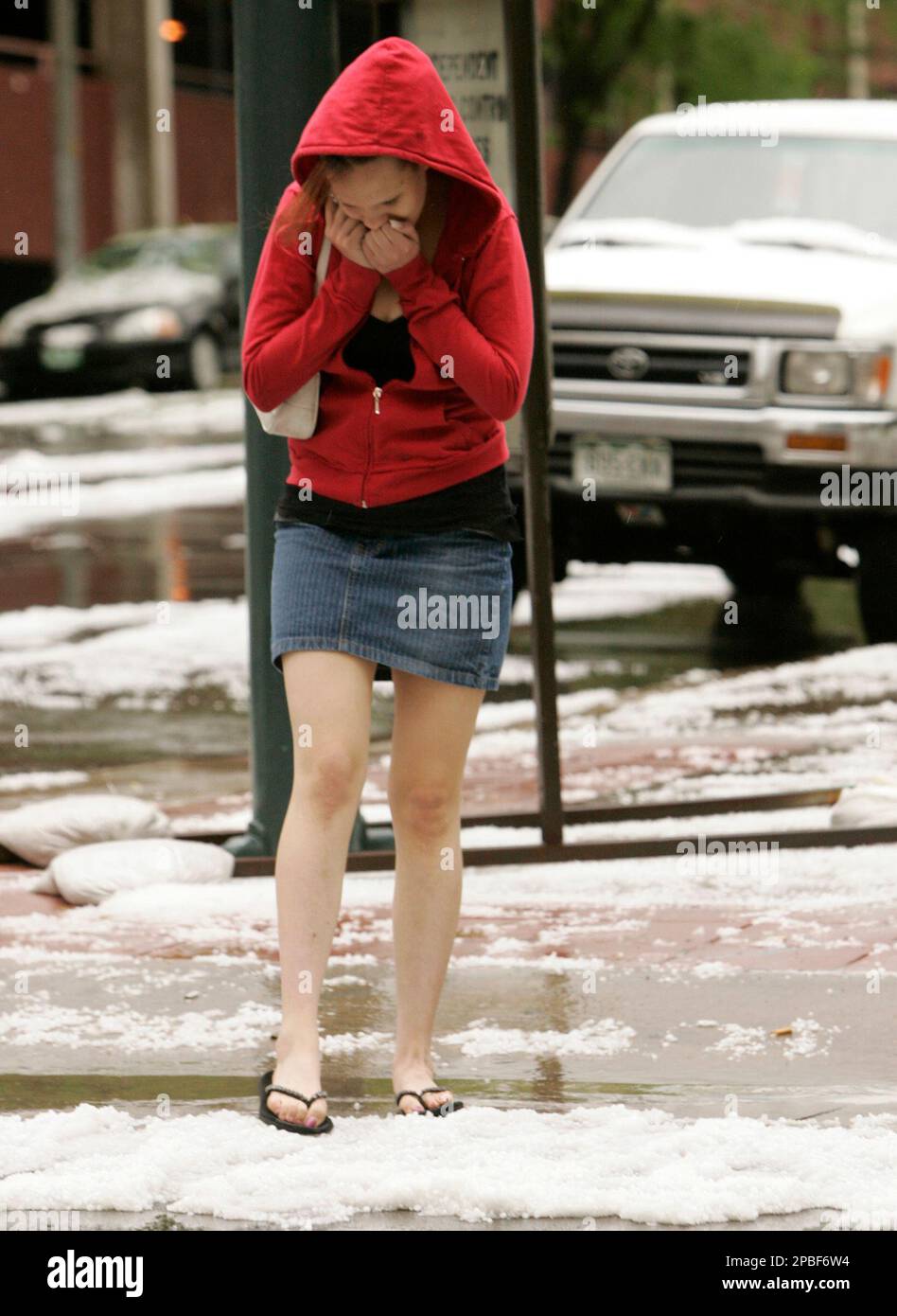 A woman wearing flip-flops walks through a pile of hail after a storm ...