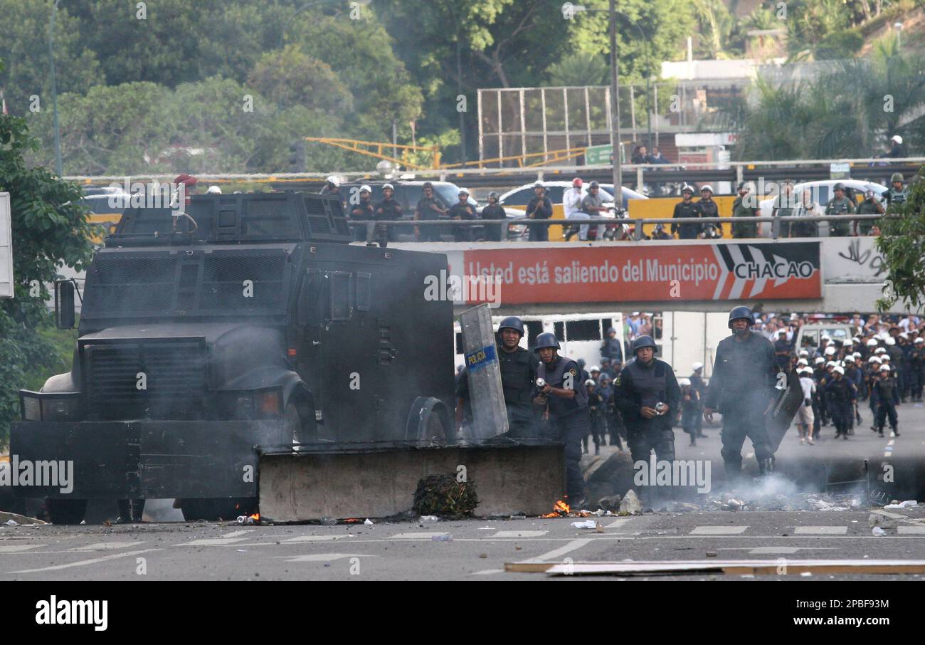 Riot police use a water canon truck to help remove a barricade made by ...