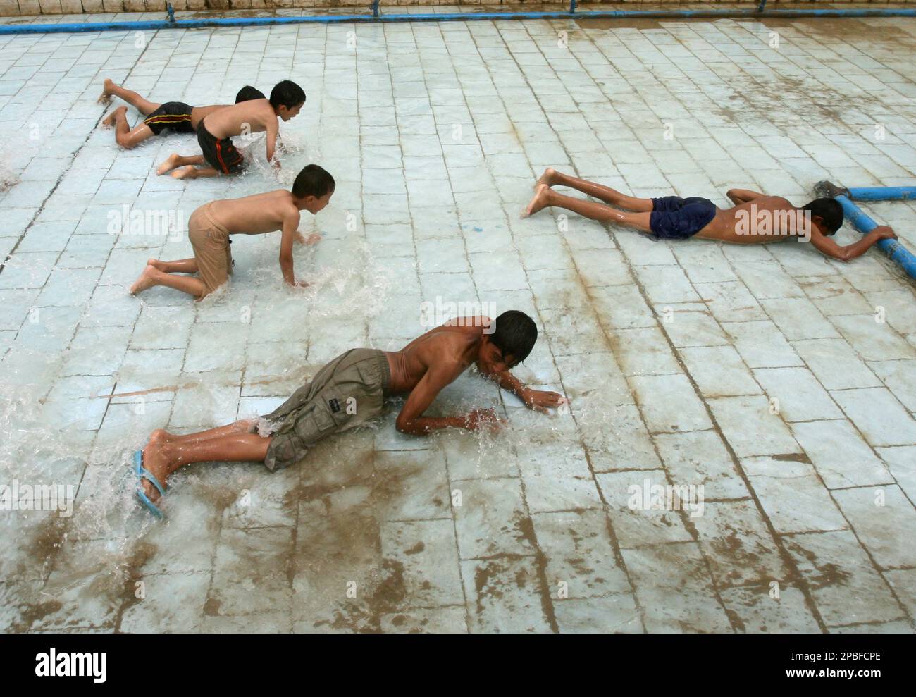 Iraqi children play inside a water fountain at Firdos square in front ...